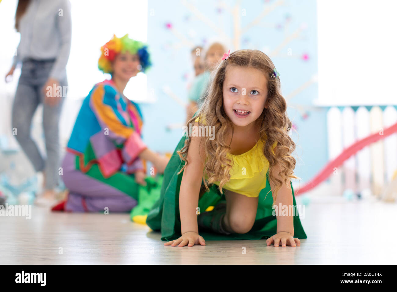 Portrait of happy kid girl scrambling in tunnel during birthday party ...