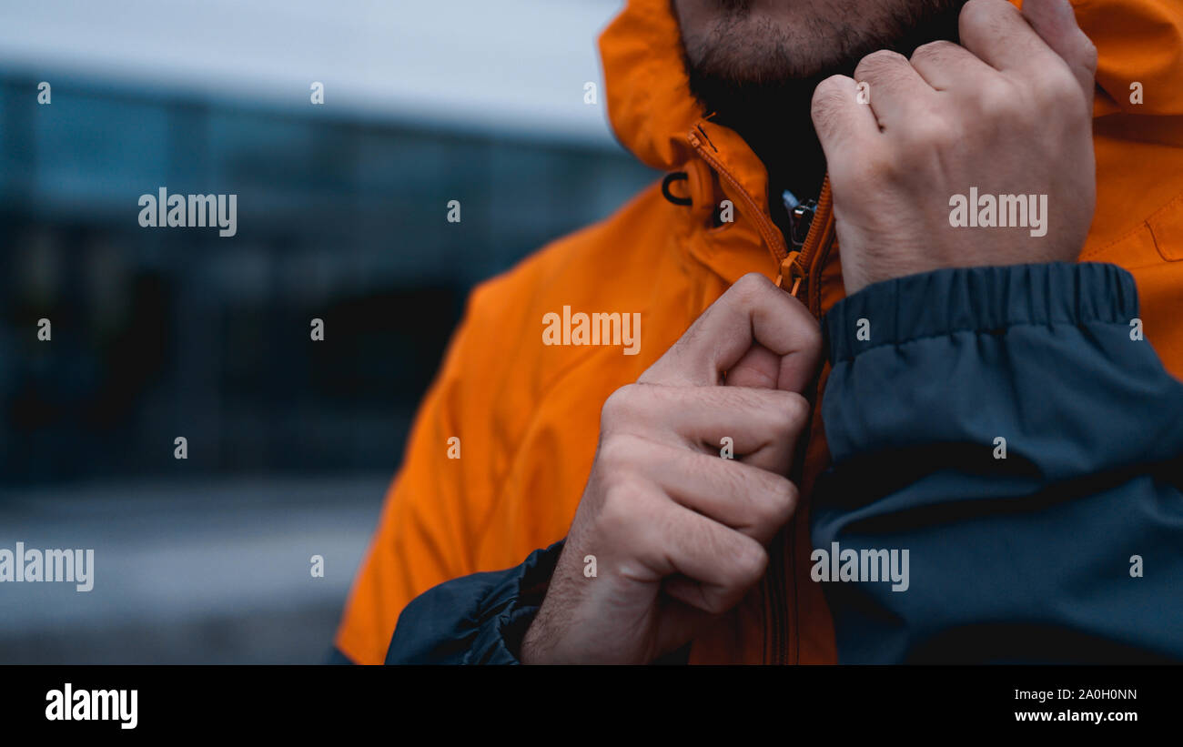 A man fastens his work uniform. Orange worker uniform - hands close up ...