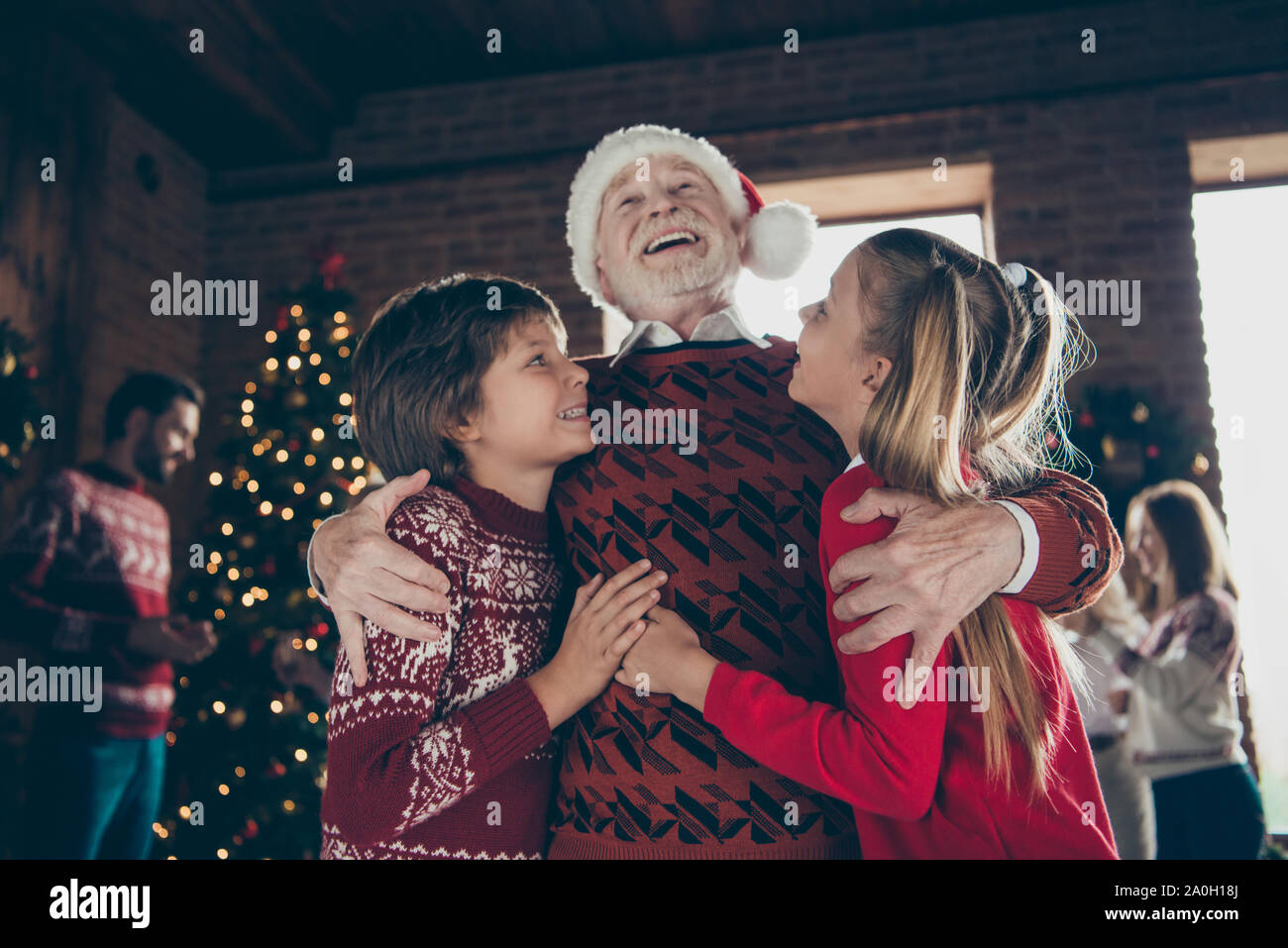 Low angle view of cheerful grandpa in headwear hugging grandchildren ...