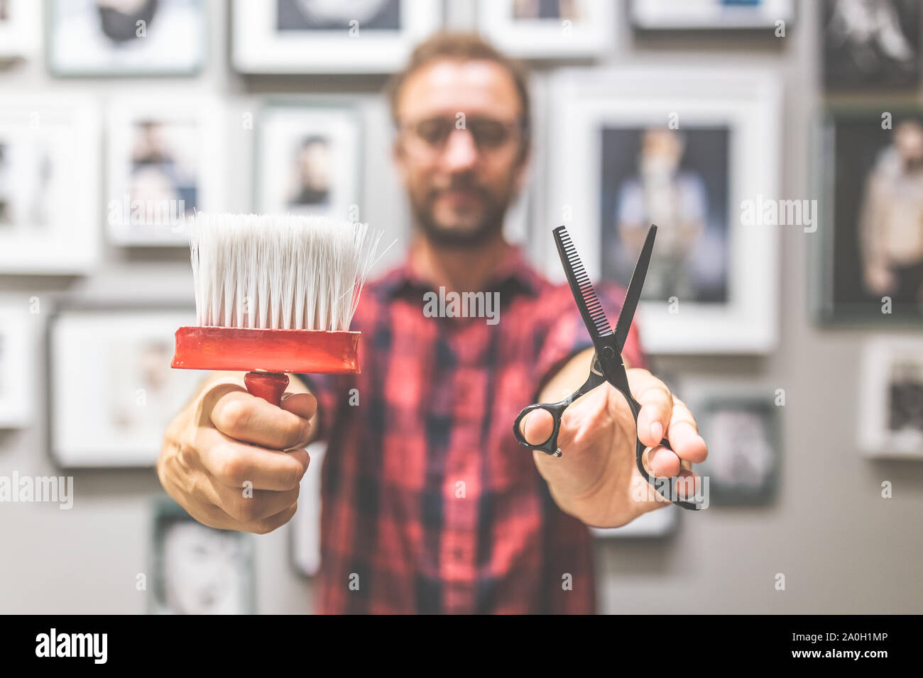 Modern barber holding cleaning brush and scissors at barbershop Stock ...