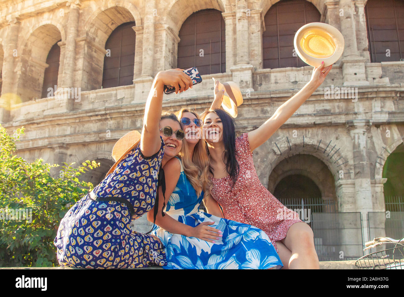 Three happy young women friends tourists taking selfies sitting at ...