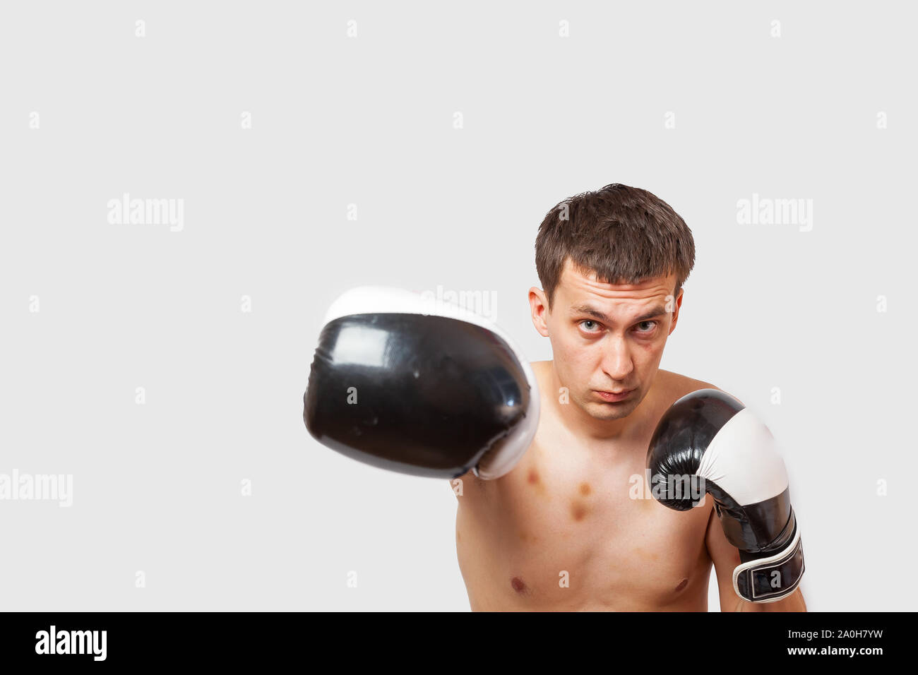 A man in boxing gloves with bruises on his body and face stabs during a ...