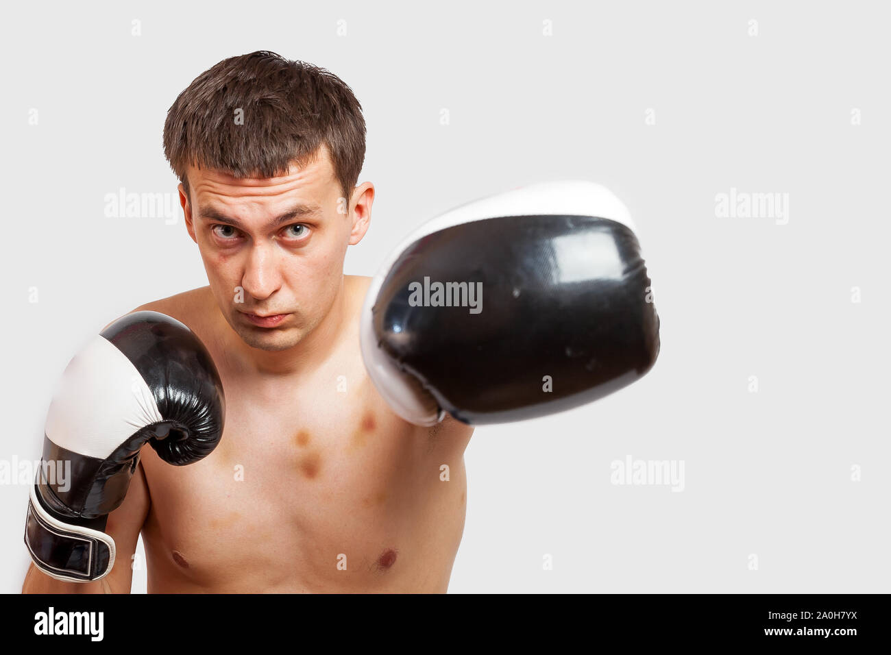 A man in boxing gloves with bruises on his body and face stabs during a ...