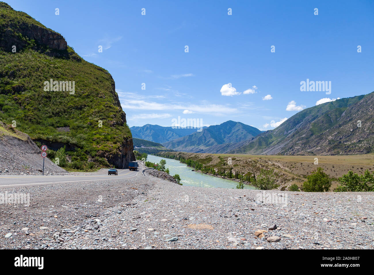 A new winding asphalt black road with a yellow dividing strip between ...