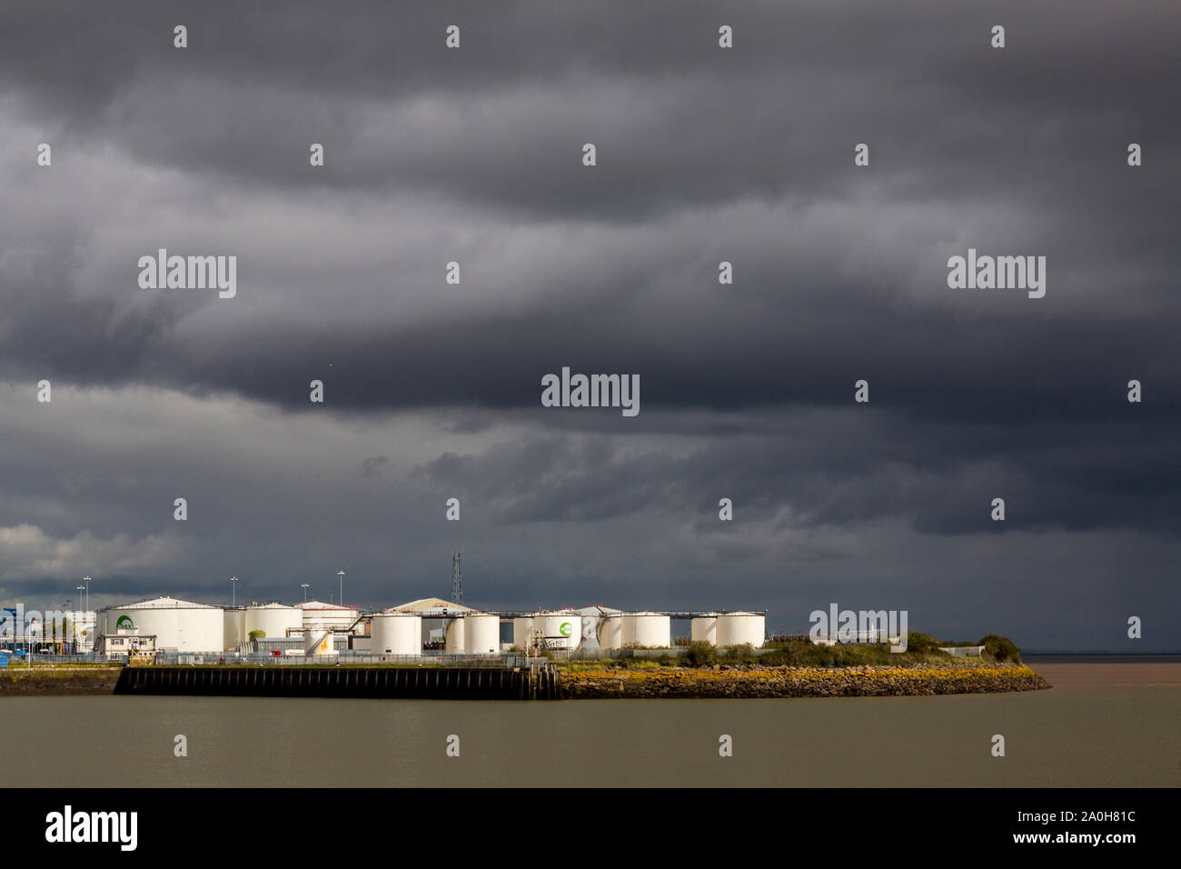 A collection of oil storage tanks under an approaching thunderstorm at ...
