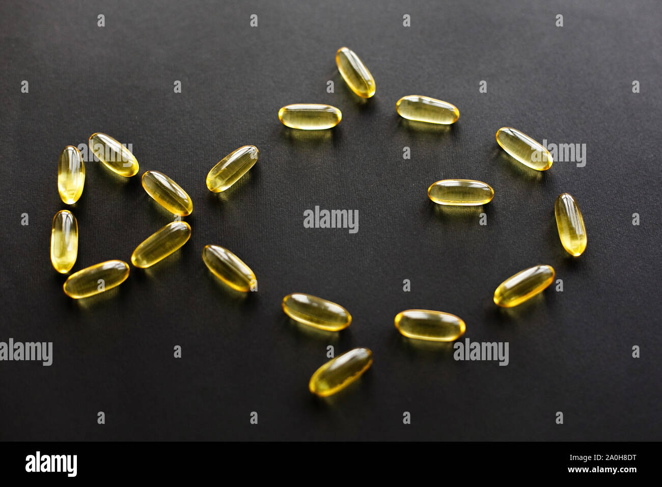 Omega 3 concept. Omega capsules in fish shape on black dark background ...