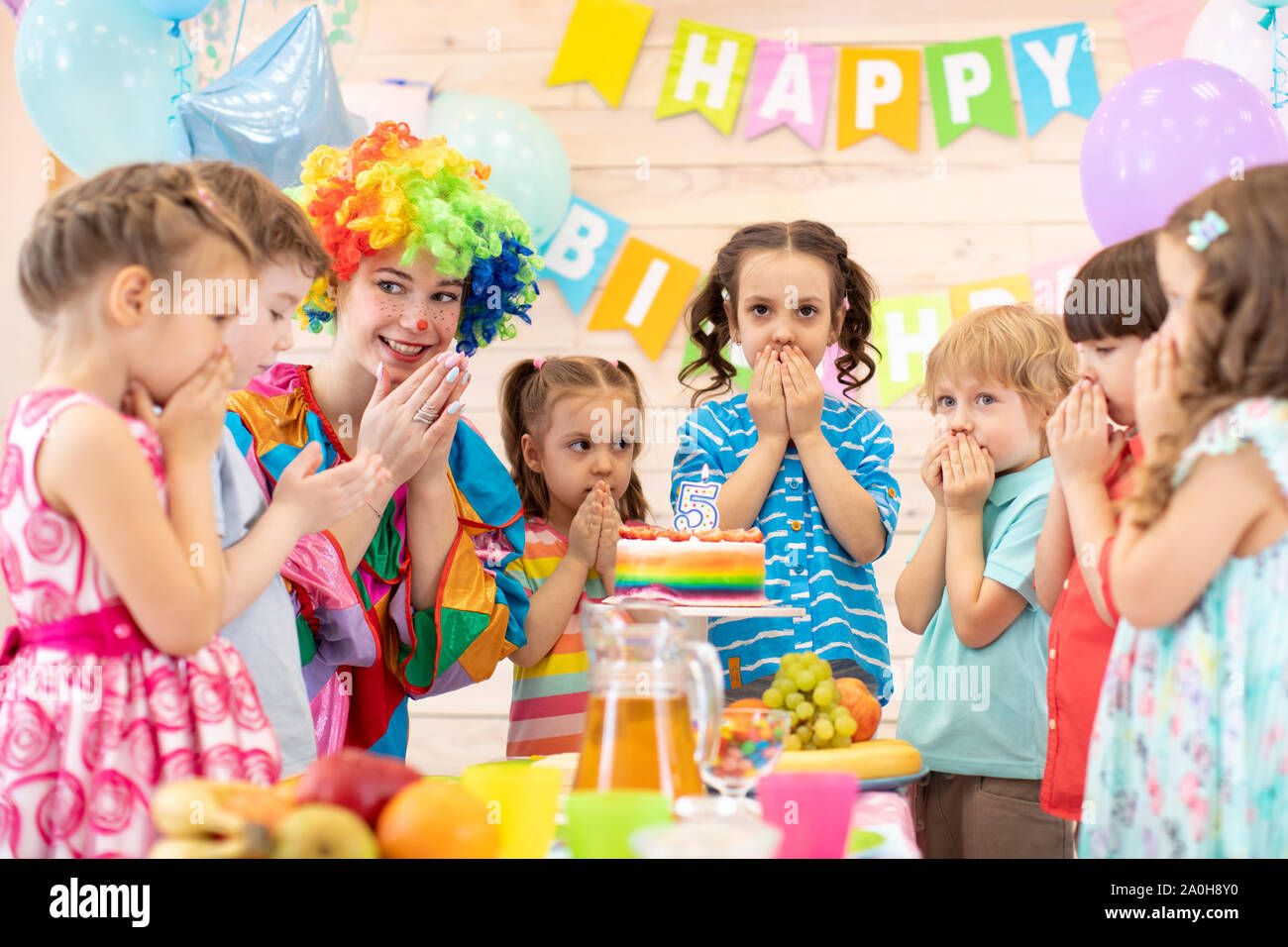 Children with clown celebrating birthday party. Group of kids stand ...