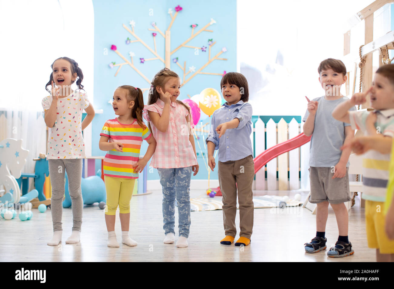 Preschool children standing on floor in kindergarten or day care centre ...