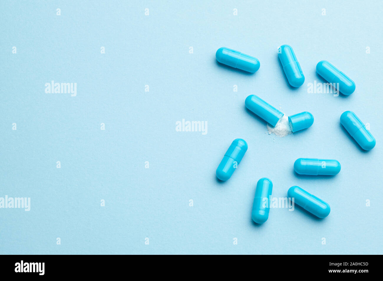 Blue tablets in capsules. One capsule is open. Blue background. Copy ...