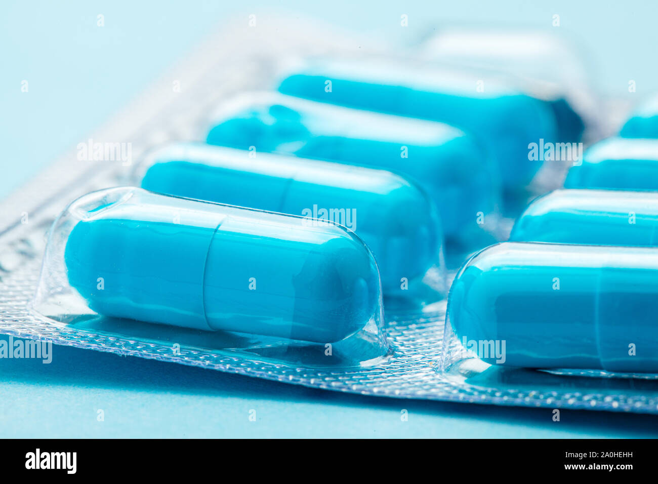 Blue tablets in capsules. One capsule is open. Blue background Stock ...