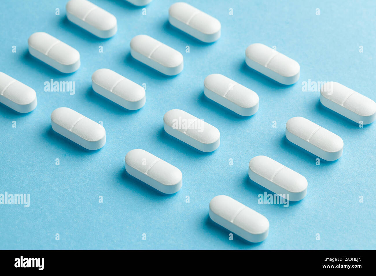 White pills on blue background Stock Photo - Alamy