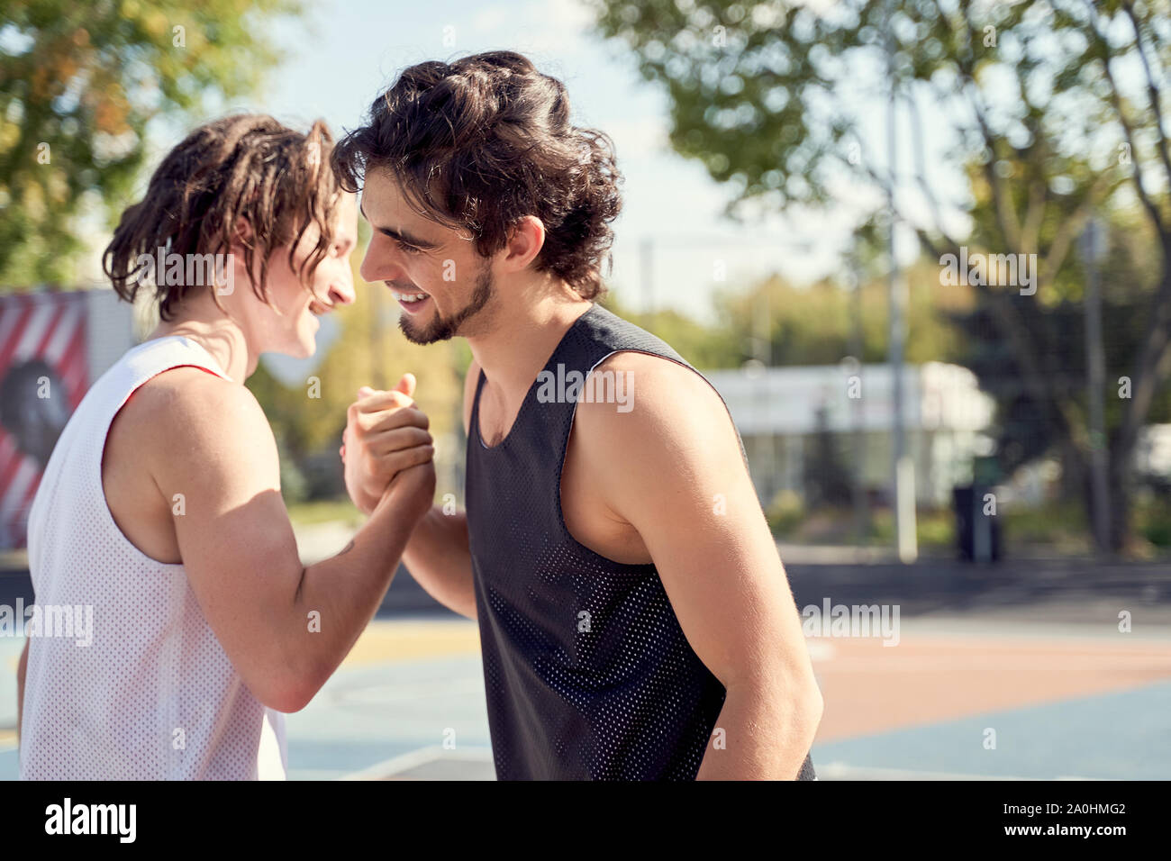 Image of happy two athletes shaking hands on sports field on summer day ...