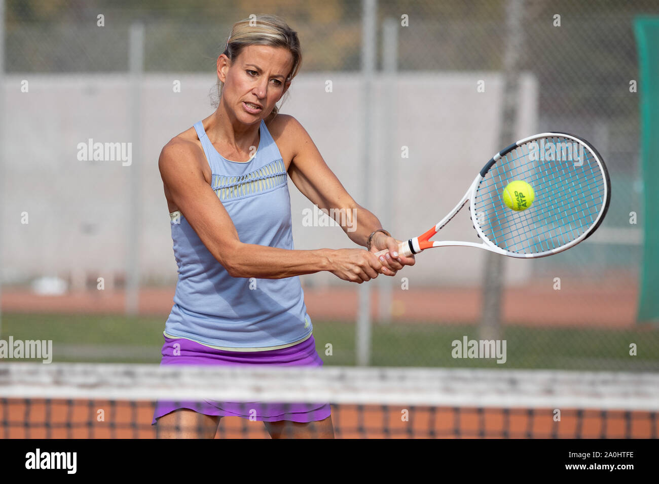Woman playing tennis hitting a backhand shot Stock Photo - Alamy
