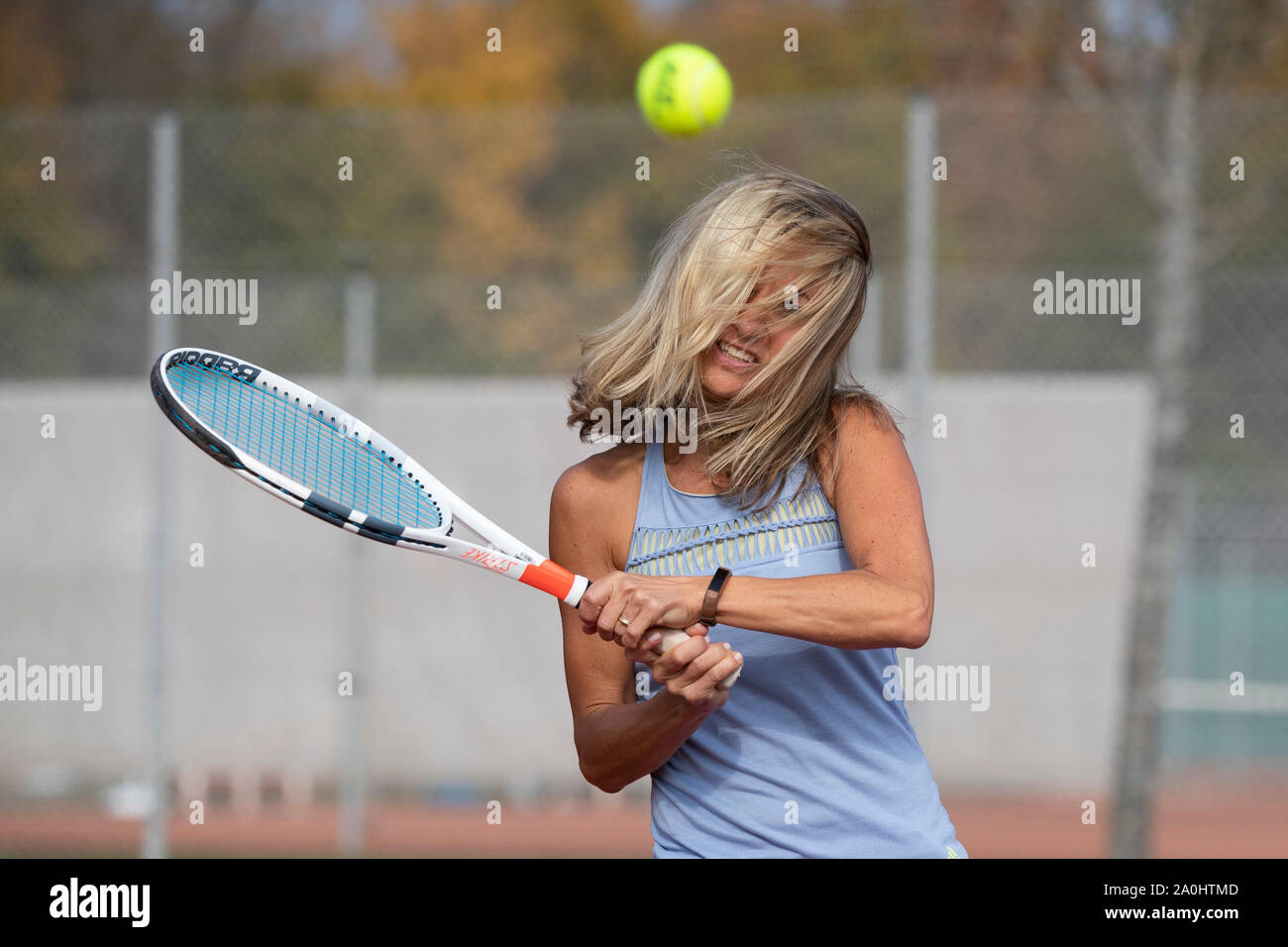 Woman playing tennis hitting a backhand shot Stock Photo - Alamy