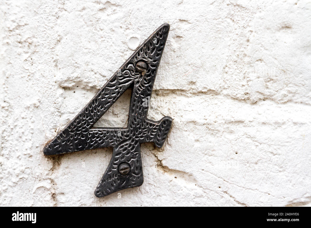 Iron house number 4 on a white plaster wall Stock Photo - Alamy