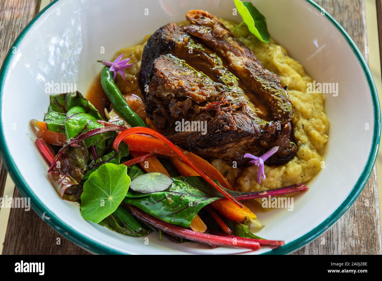 Plate of lamb shoulder with tsukini baba ganoush Stock Photo - Alamy