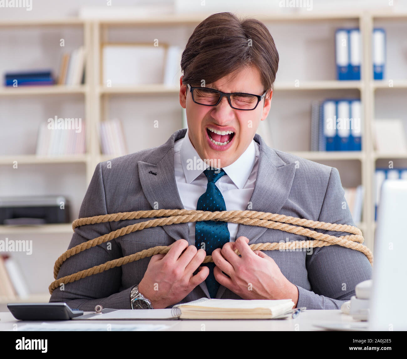 The businessman tied up with rope in office Stock Photo - Alamy