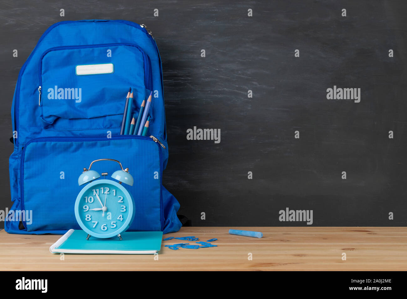 Back to school. Backpack, alarm clock and books Sky blue tone on ...