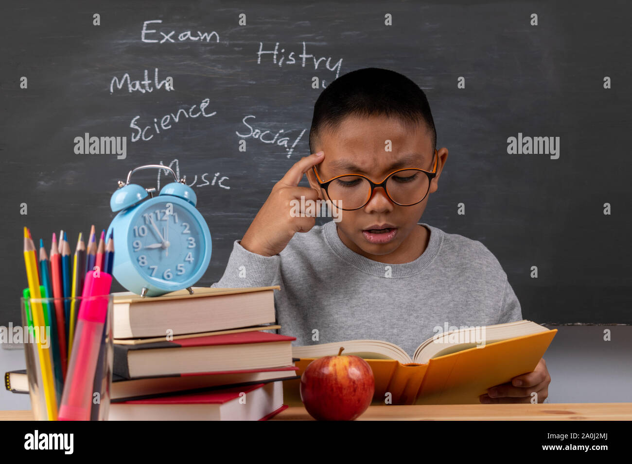 School boy reading book in classroom with chalkboard background ...