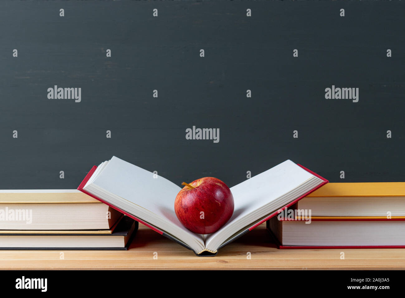 School books, apple, chalkboard with "back to school" on background ...