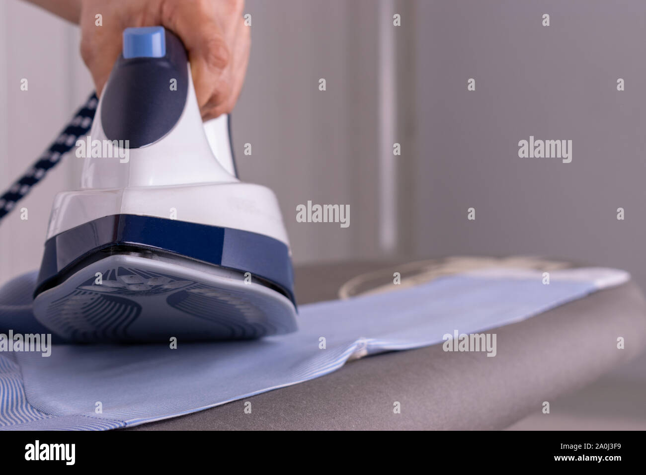 Close-up woman ironing clothes on ironing board in laundry room at home ...