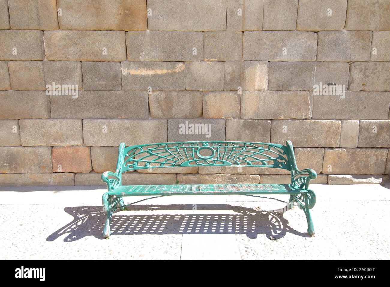 Green steel bench in stone wall background Stock Photo - Alamy