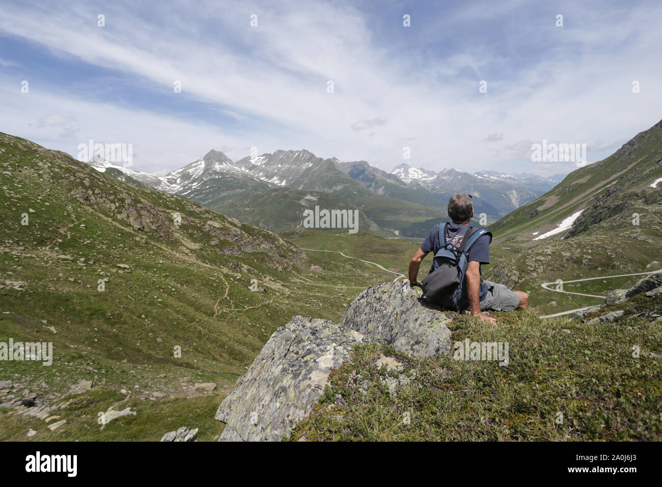 A man sitting on a rock face appreciating the alpine scenery Stock ...