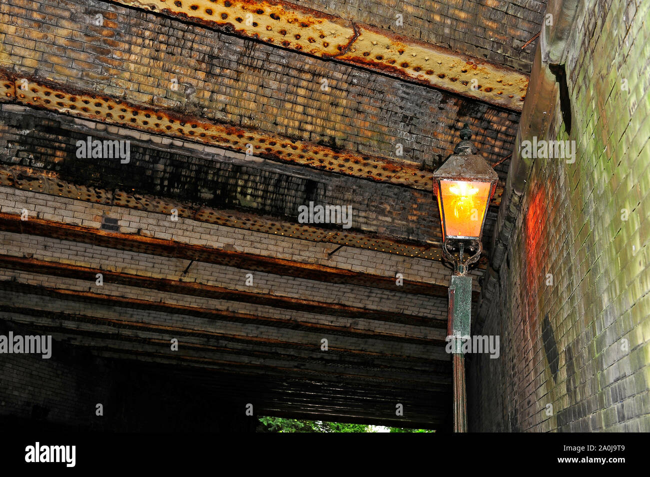 Old Victorian lamp post lighting the gloom underneath a brick and iron ...
