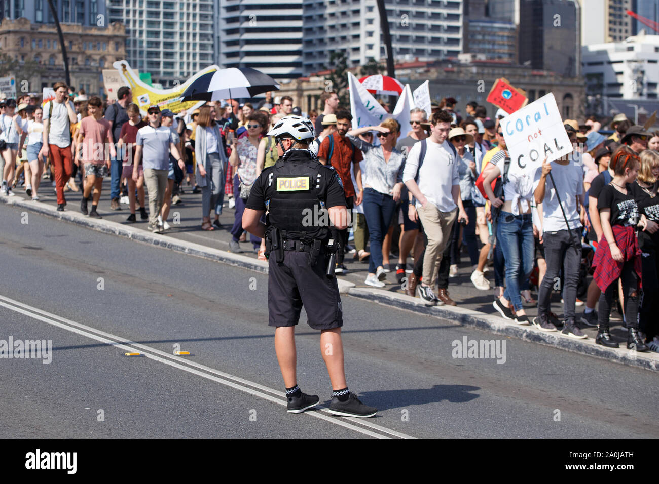 Brisbane, Australia. 20th Sep, 2019. Protesters march while a policeman ...