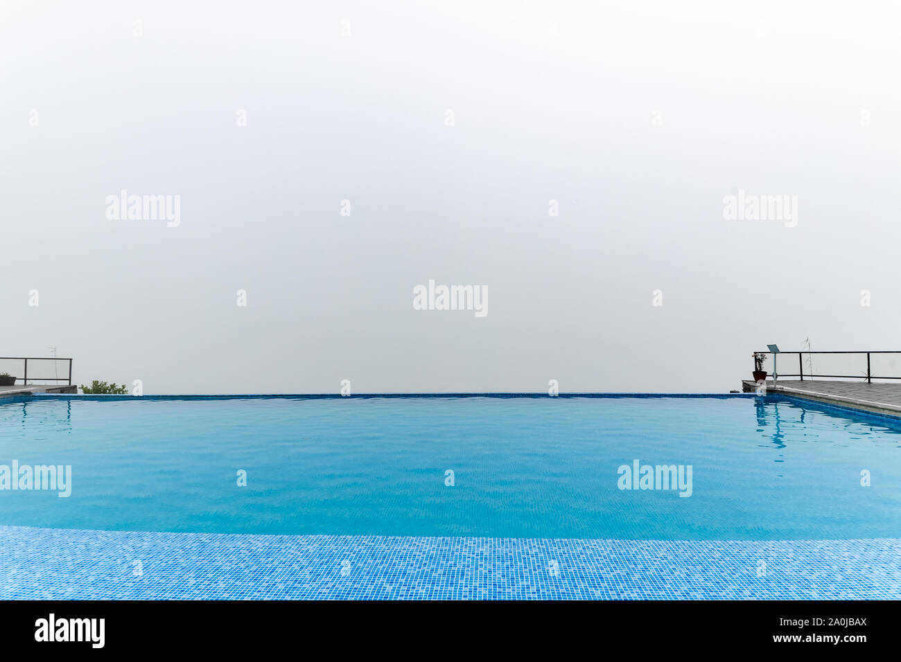 Infinity swimming pool with foggy white background Stock Photo - Alamy