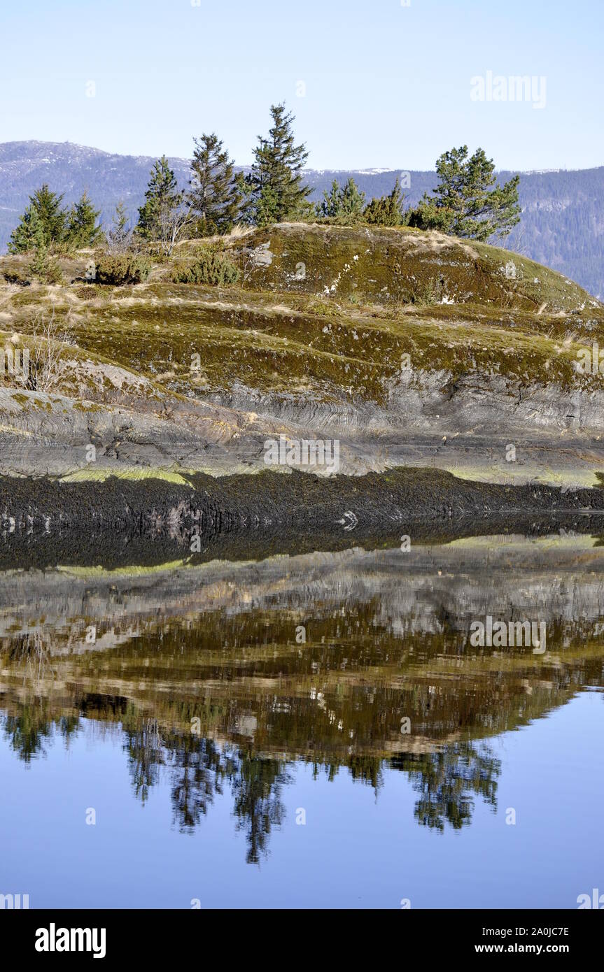 Landscape reflected in still blue water Stock Photo - Alamy