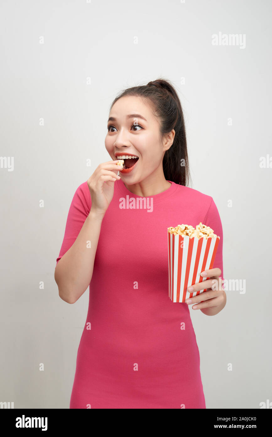 Portrait of a cheery pretty girl eating popcorn isolated over white ...