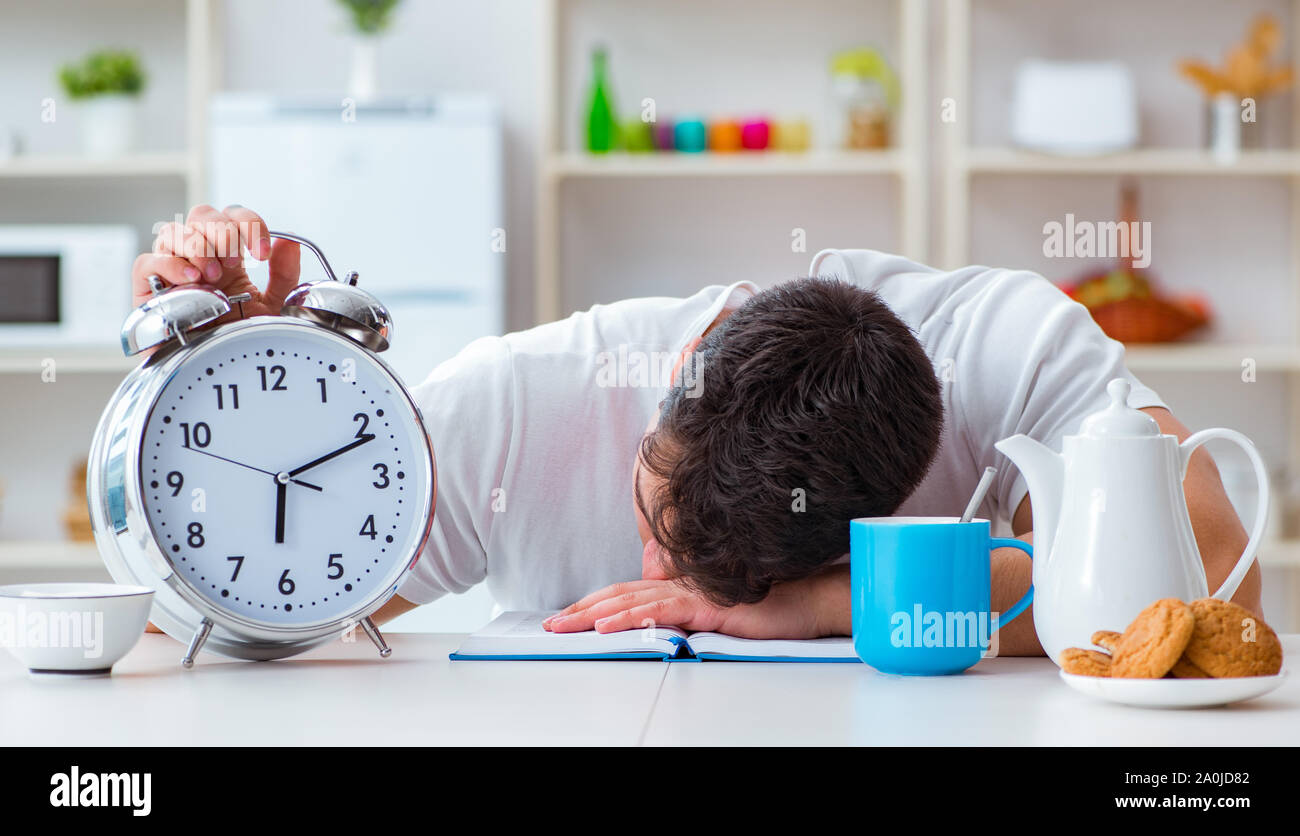 The man with alarm clock falling asleep at breakfast Stock Photo - Alamy
