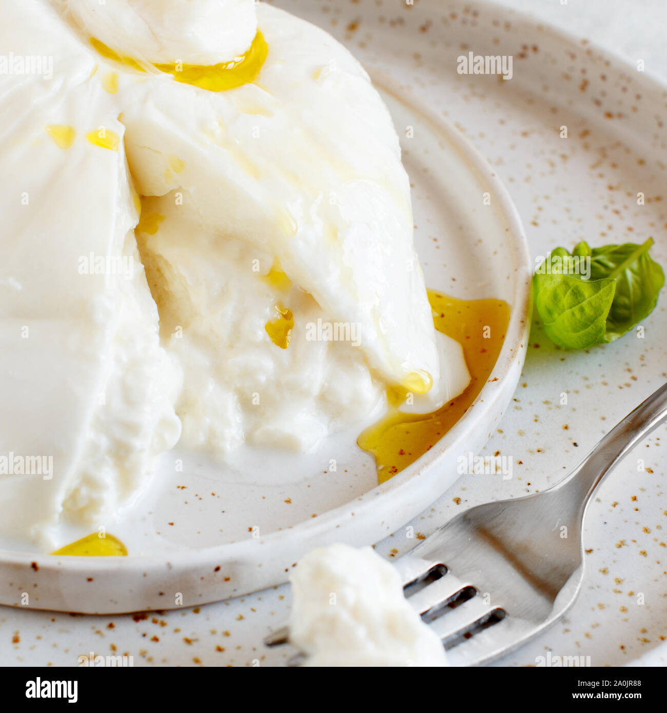 Italian cheese burrata on a plate with a fork and basil Stock Photo - Alamy