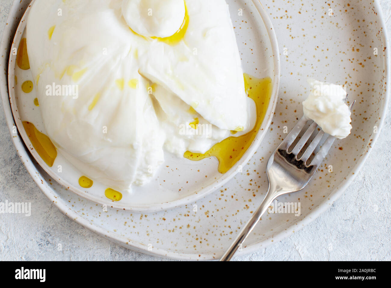 Italian cheese burrata on a plate with a fork and olive oil Stock Photo ...