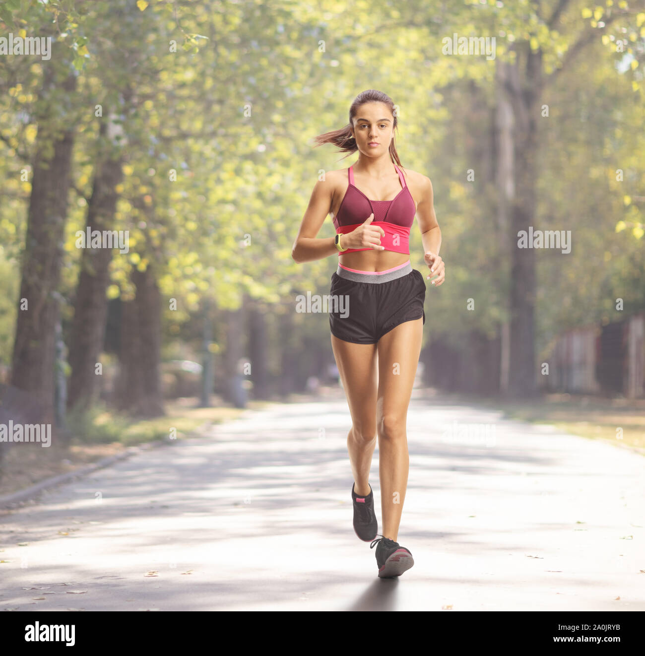 Full length portrait of a young female athlete jogging outdoors Stock ...