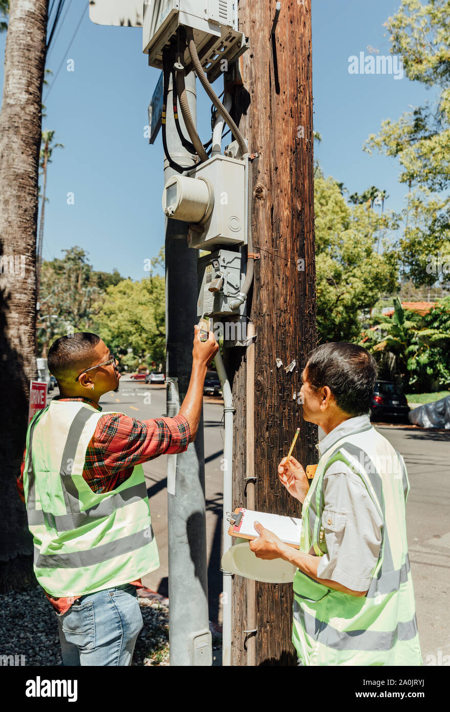 Men working together on a telephone pole Stock Photo - Alamy
