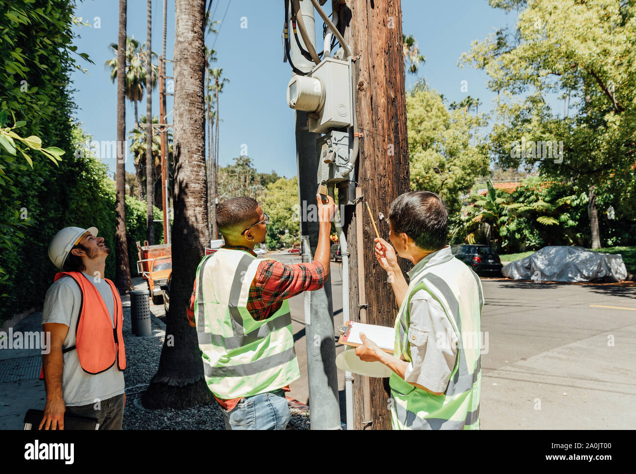 Men working together on a telephone pole Stock Photo - Alamy