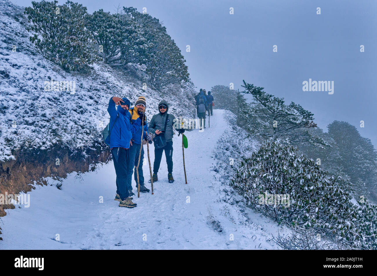 Hikers are taking selfie while walking through a snowy mountain trail ...