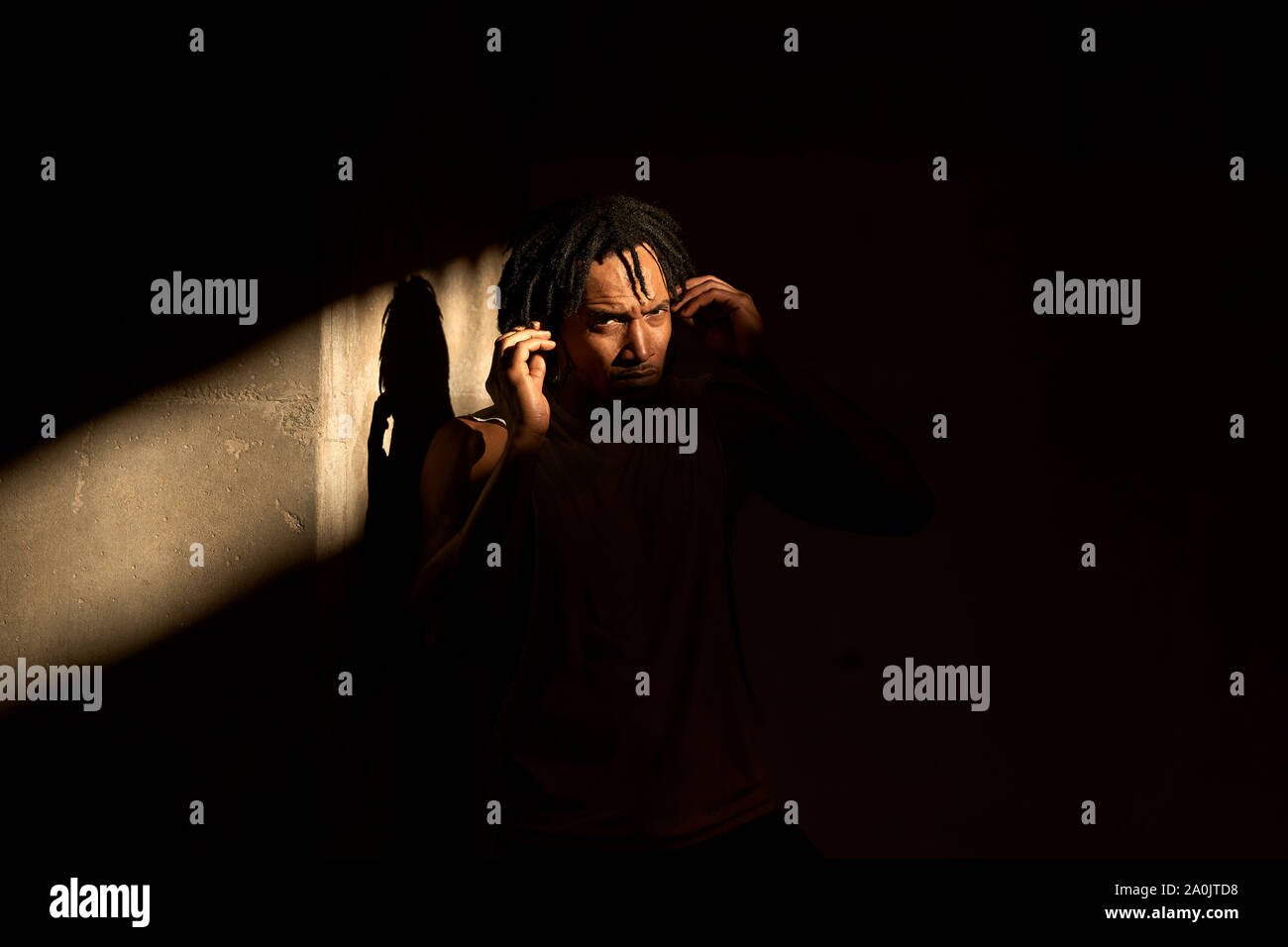 African-American man adjusting earbuds in sunbeam Stock Photo - Alamy