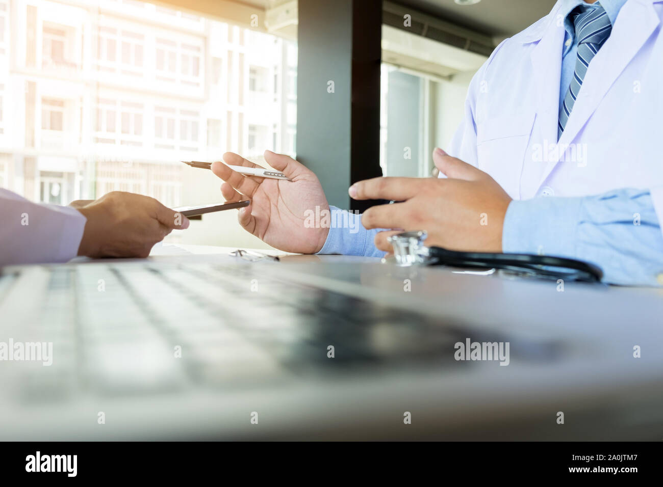 Two doctors discussing patient notes in an office pointing to a ...