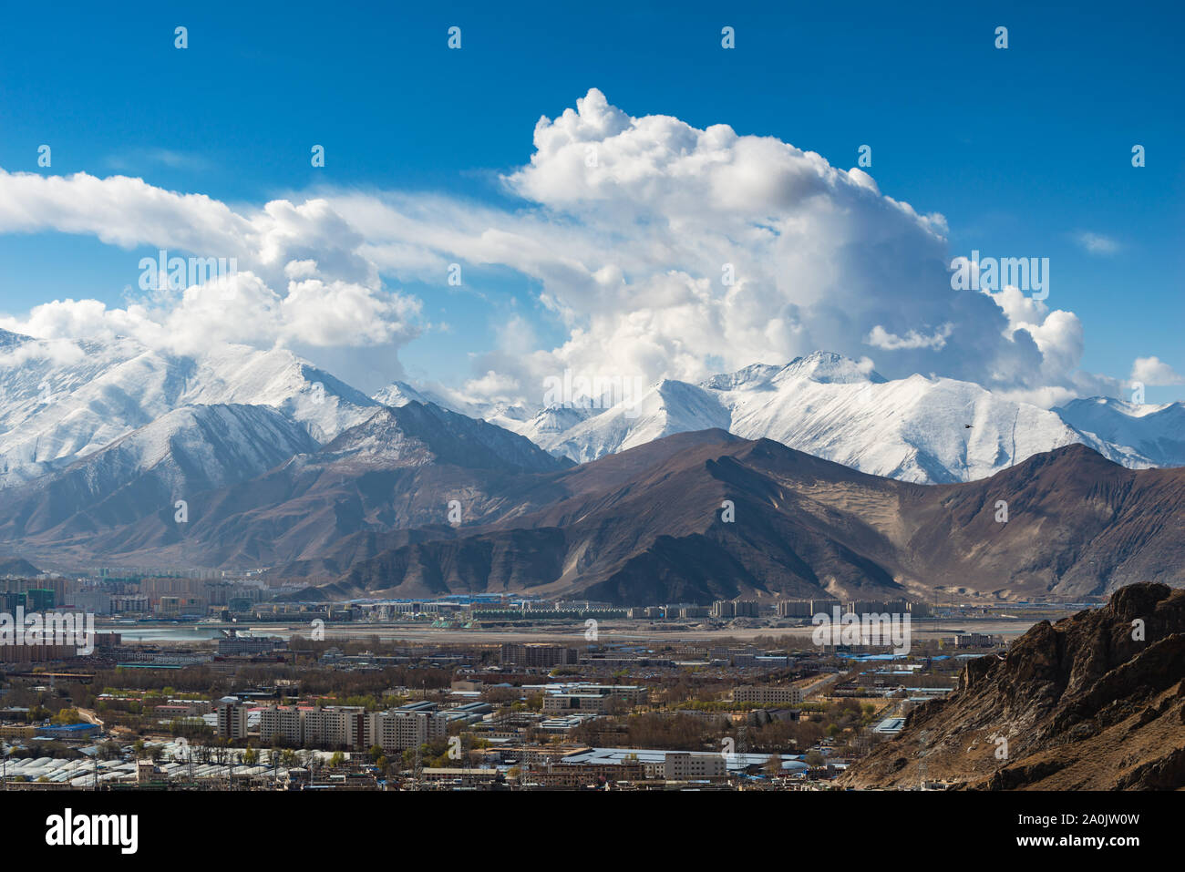 Snow-capped mountains loom over the city of Lhasa in Tibet, China Stock ...
