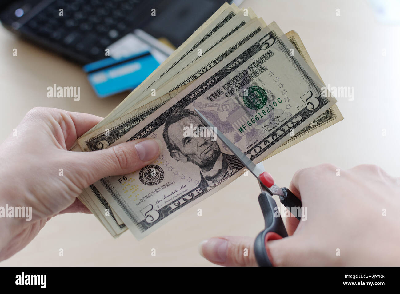 Cutting US Dollar banknote with a scissors, cut budget, reduce cost ...