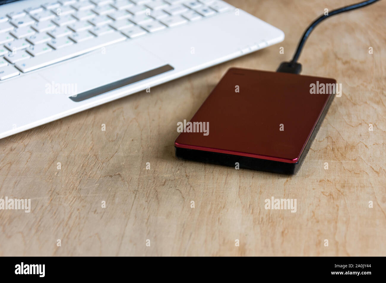 Modern storage, external hard drive and laptop keyboard on wooden table ...