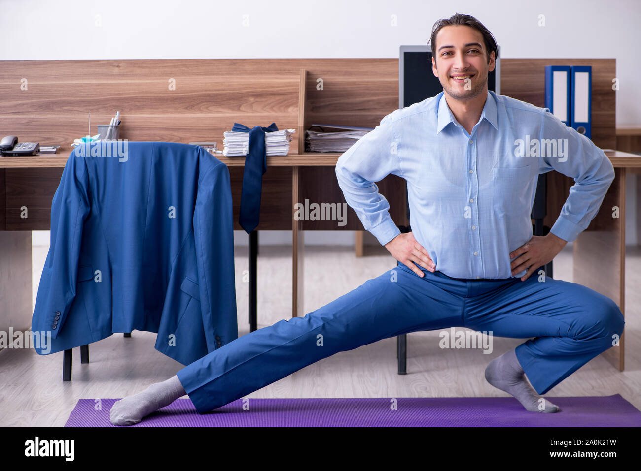 The young handsome businessman doing exercises at workplace Stock Photo ...