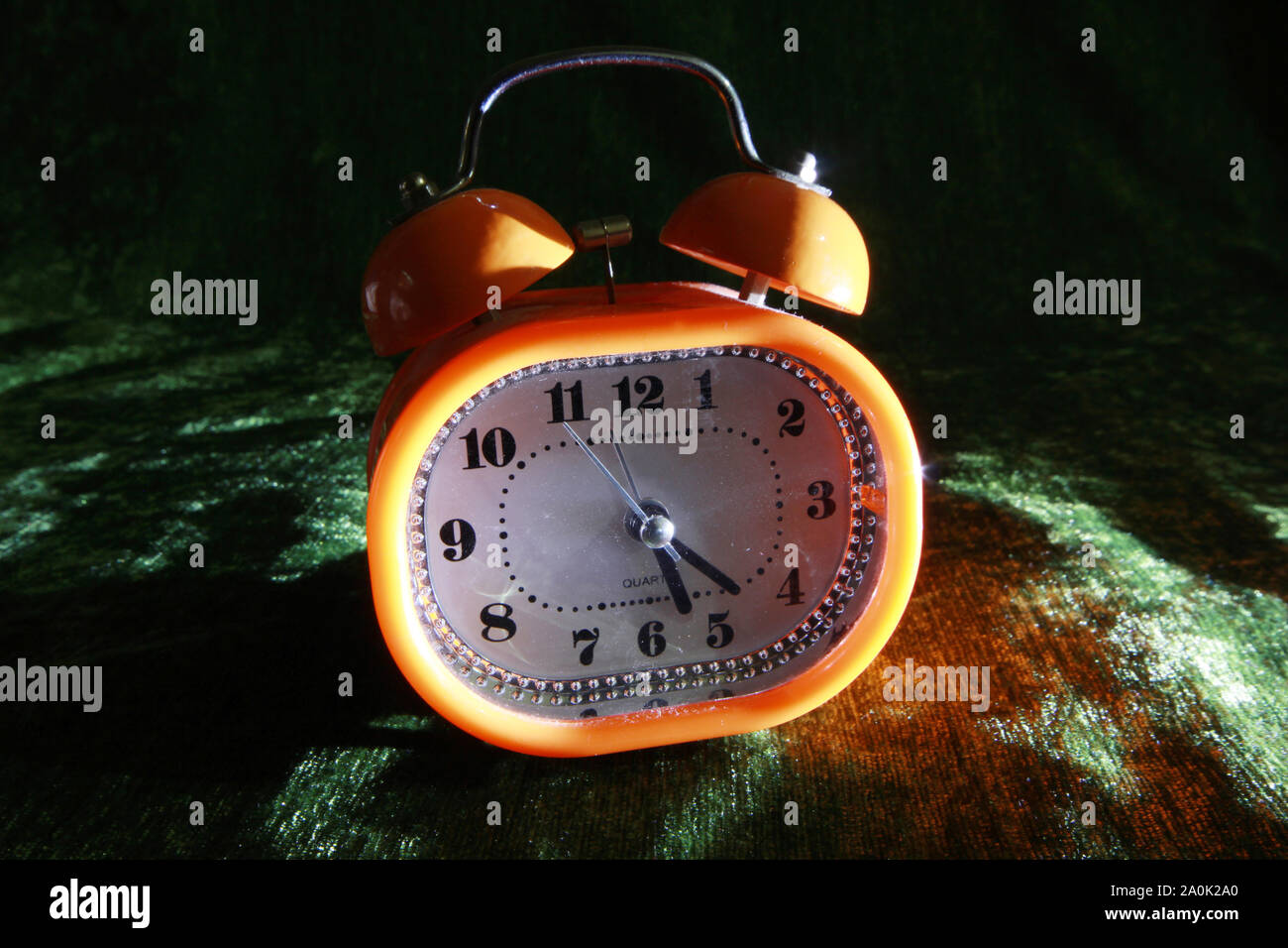 orange alarm clock on velvet fabric Stock Photo - Alamy