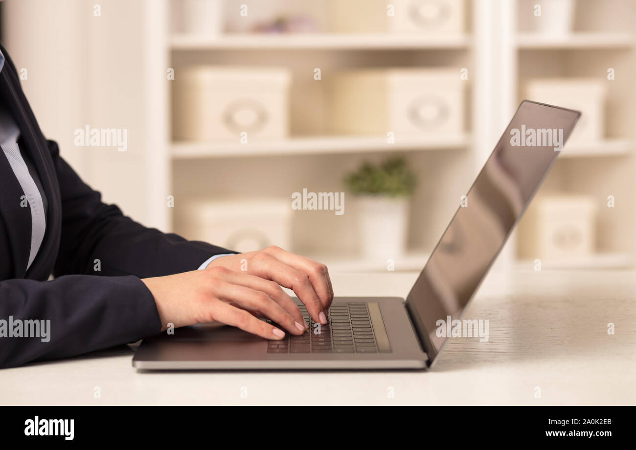 Business woman below chest working on her laptop in a cozy environment ...