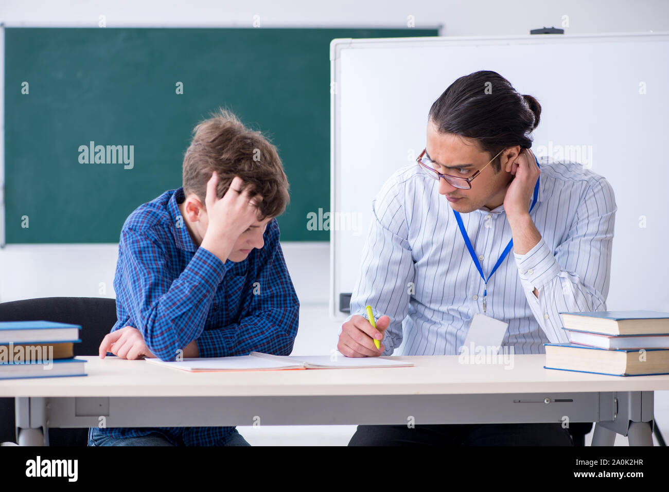 The young male teacher and boy in the classroom Stock Photo - Alamy