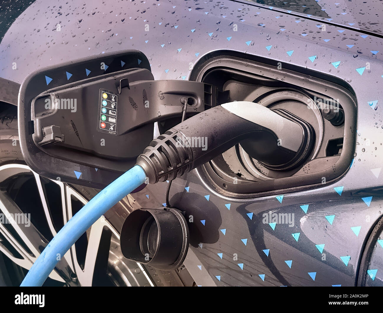 Electric vehicle being plugged in Stock Photo - Alamy