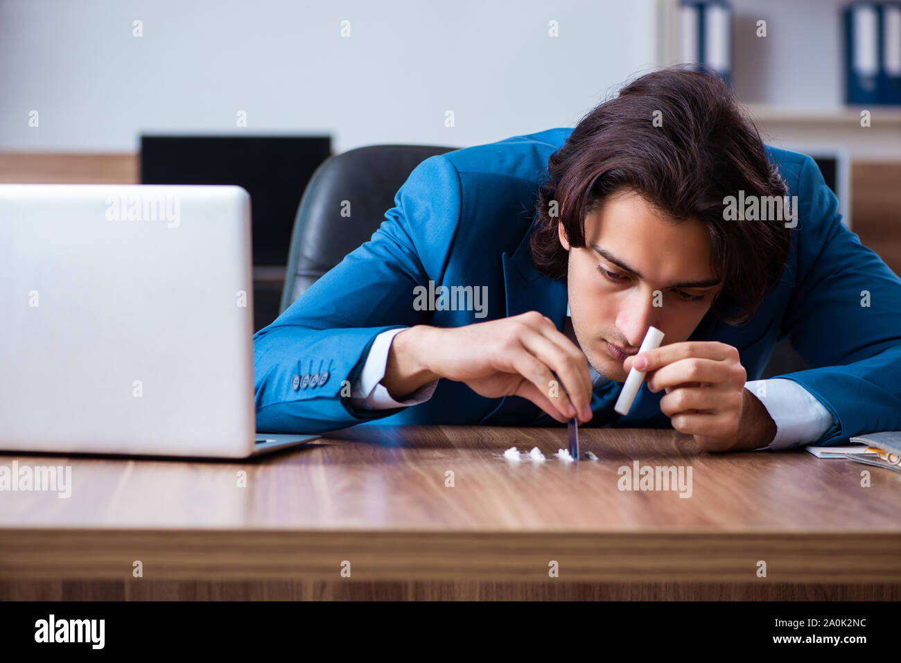 The young man having problems with narcotics at workplace Stock Photo ...